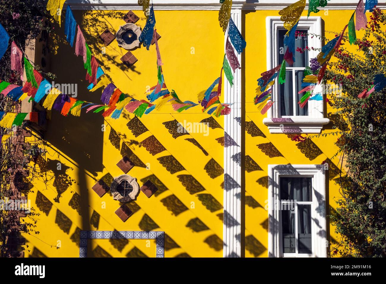 Colorful paper streamers, bright yellow wall and window, San José del ...