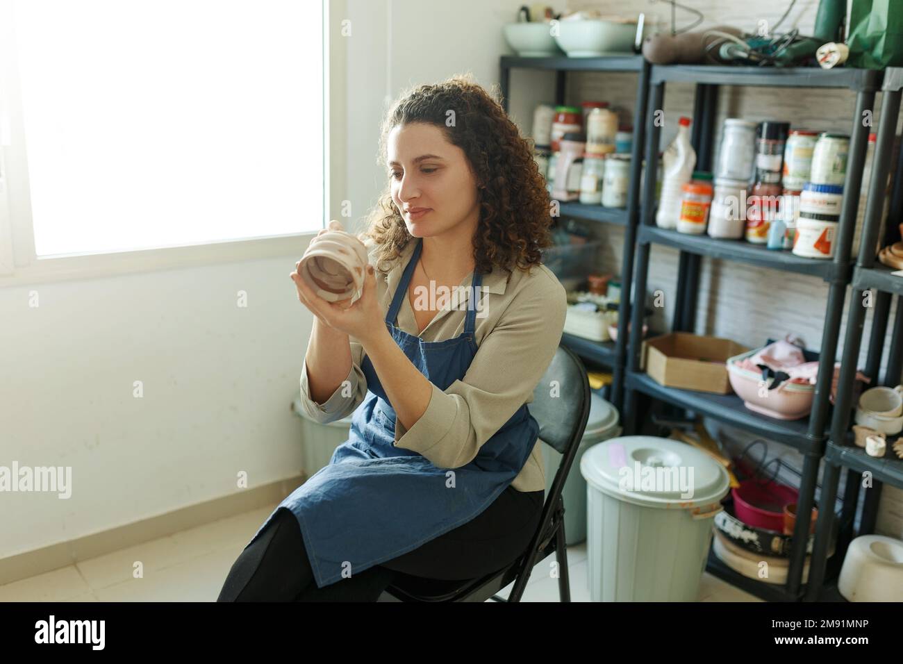 Concentrated woman painting clay jug with colourful paint shaping and ...