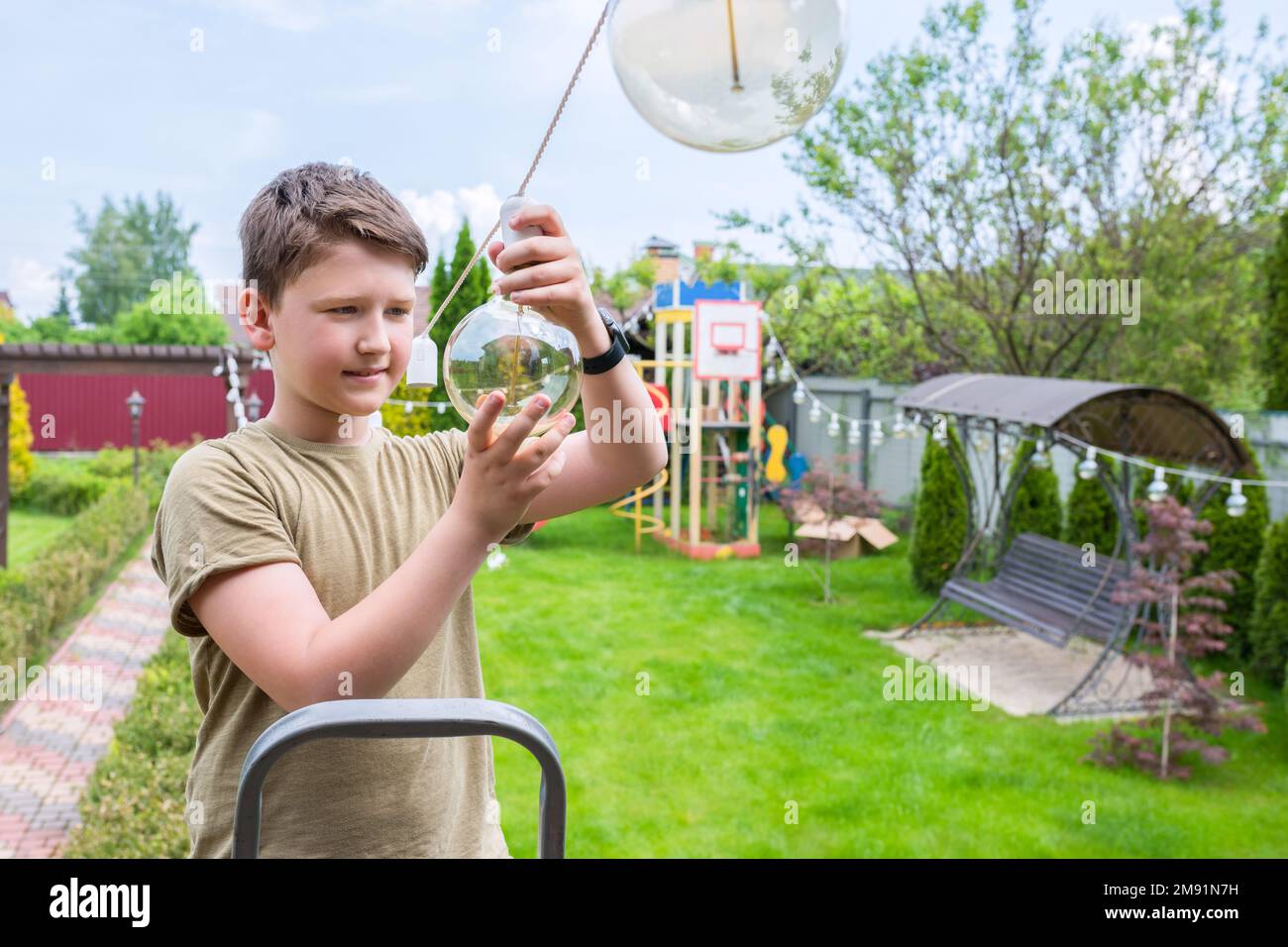 A boy in the backyard is plugging in bulbs. Cleanup in the open air ...