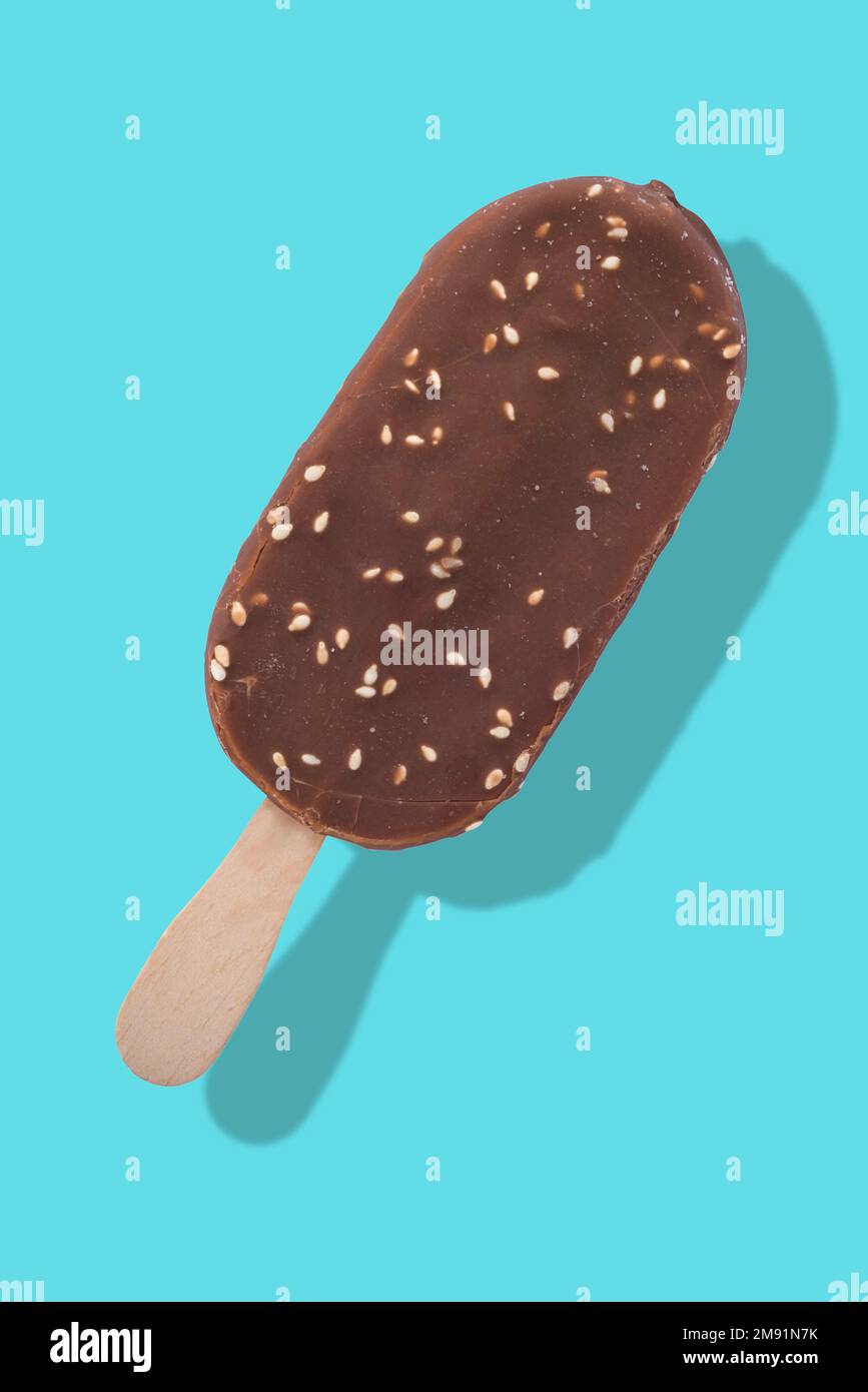 Chocolate ice cream on a stick with nuts on a blue background with a ...
