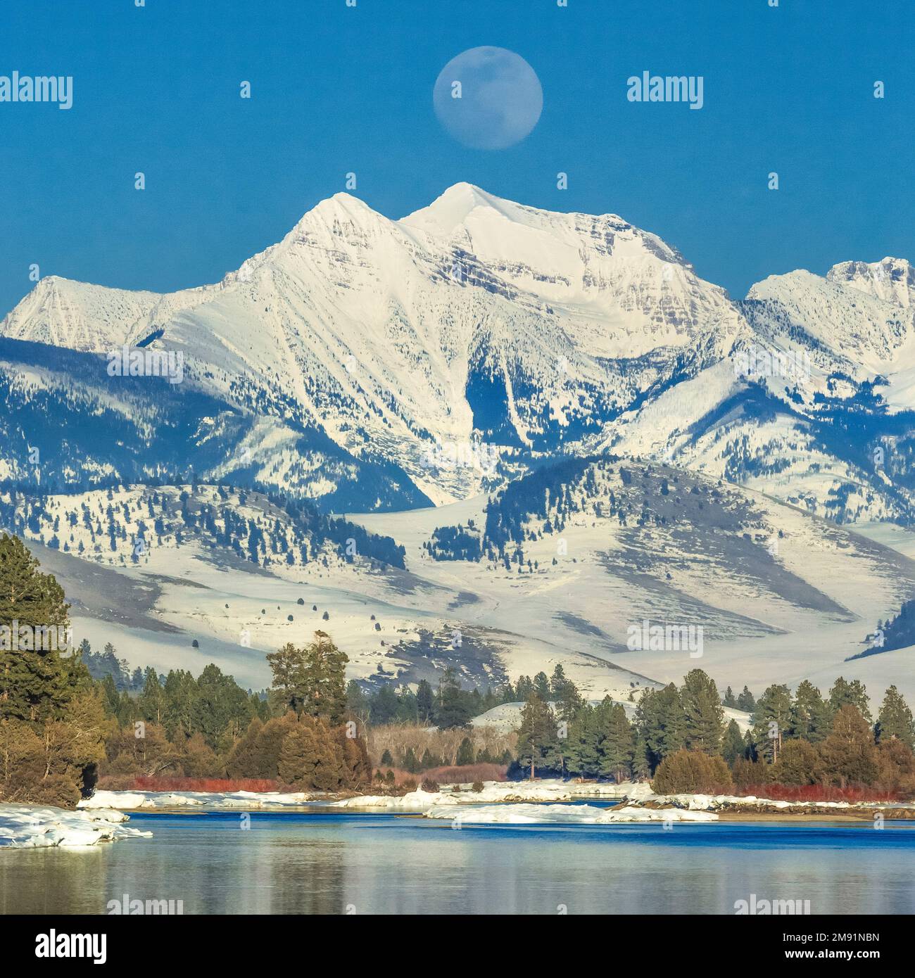 full moon rising over the flathead river and mission mountains in ...