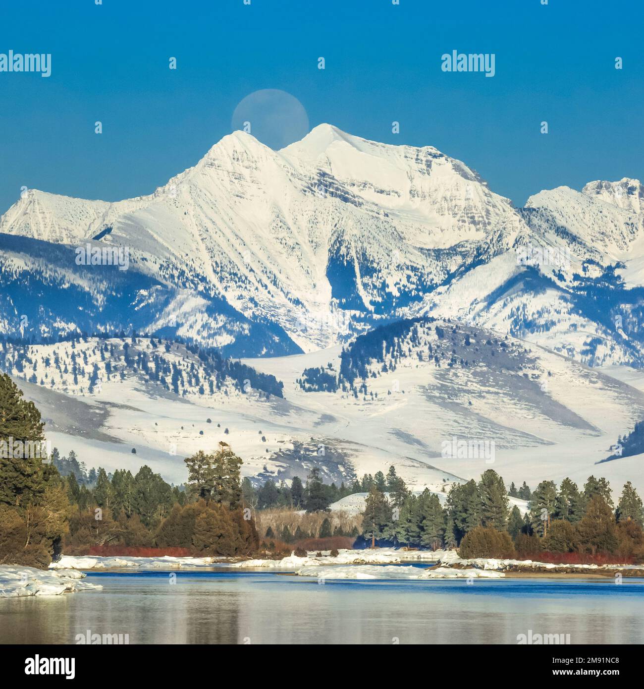 full moon rising over the flathead river and mission mountains in ...