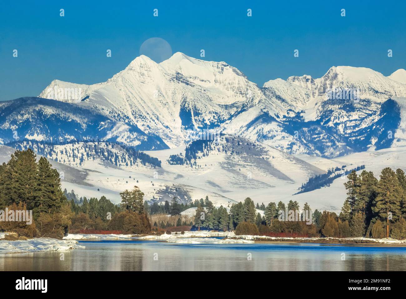 full moon rising over the flathead river and mission mountains in ...
