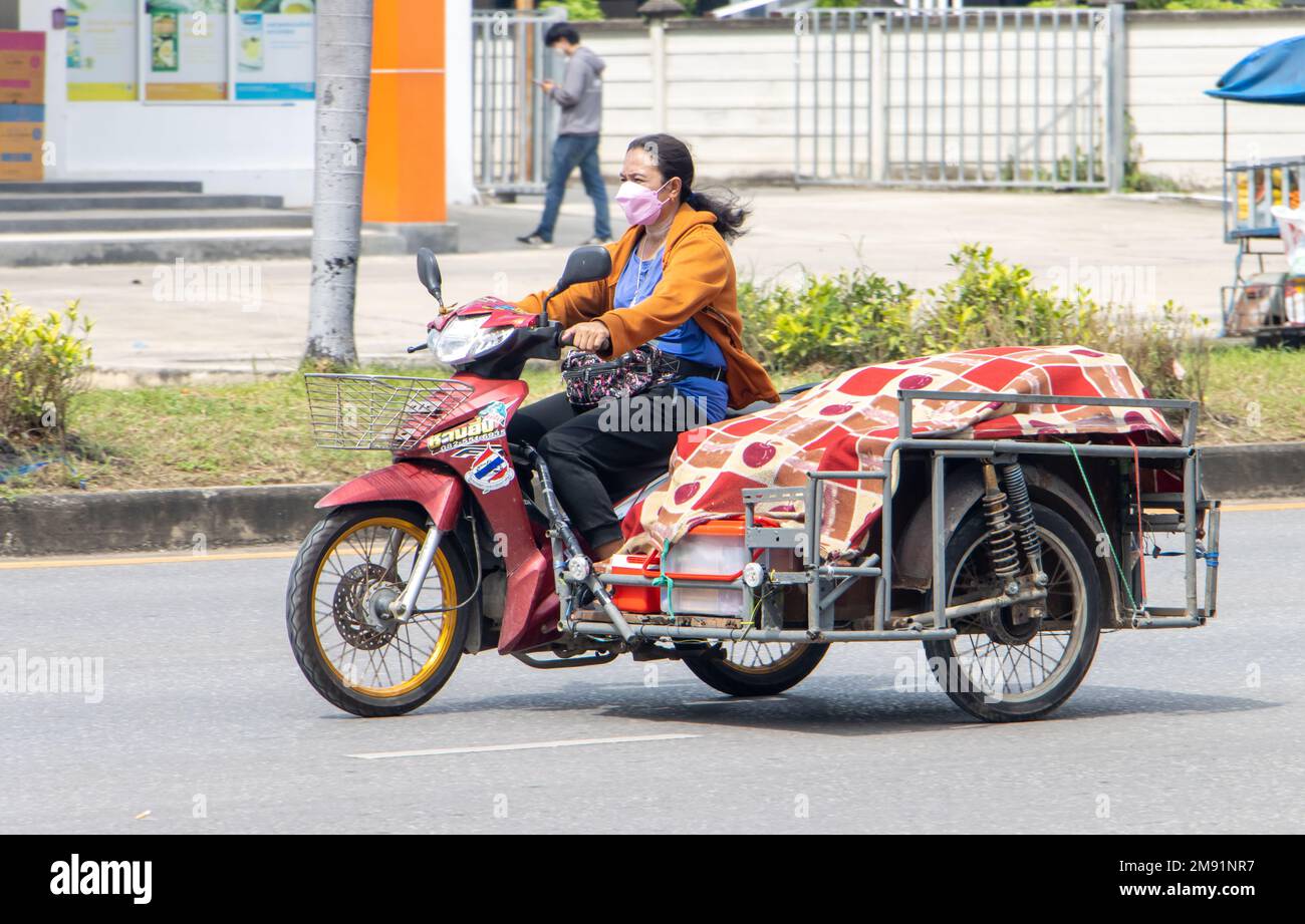 RATCHABURI, THAILAND, NOV 16 2022, A woman drives a motorcycle with an ...