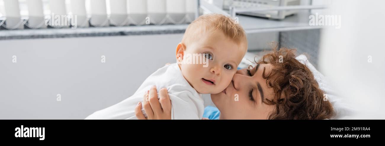 woman with closed eyes kissing baby girl in hospital ward, banner,stock ...
