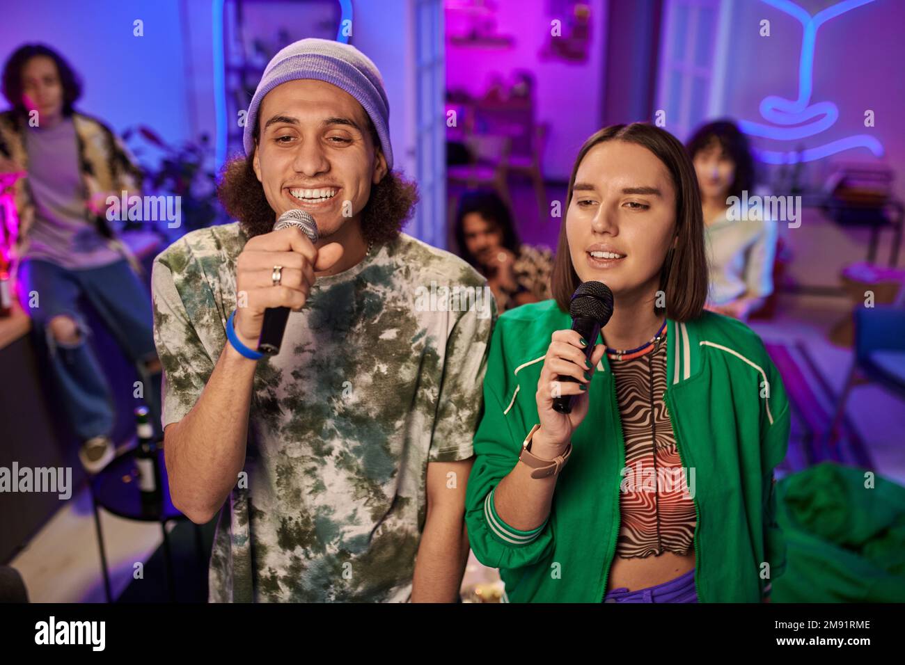 Young multicultural couple with microphones singing karaoke songs in ...