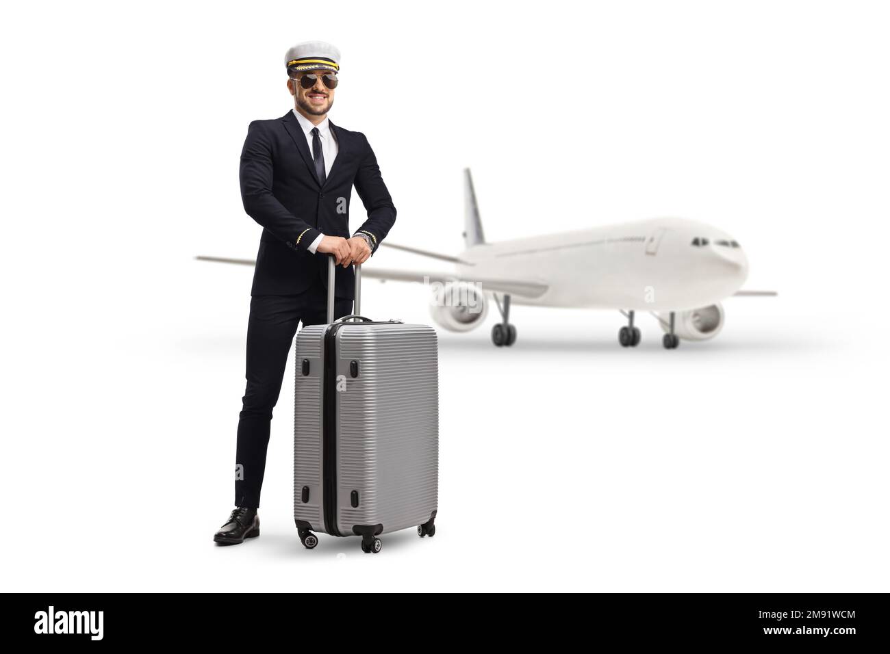 Young pilot in a uniform standing with a suitcase in front of a parked ...