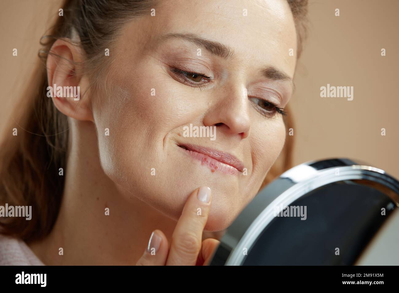 middle aged woman with herpes on lips and mirror on beige background Stock Photo - Alamy