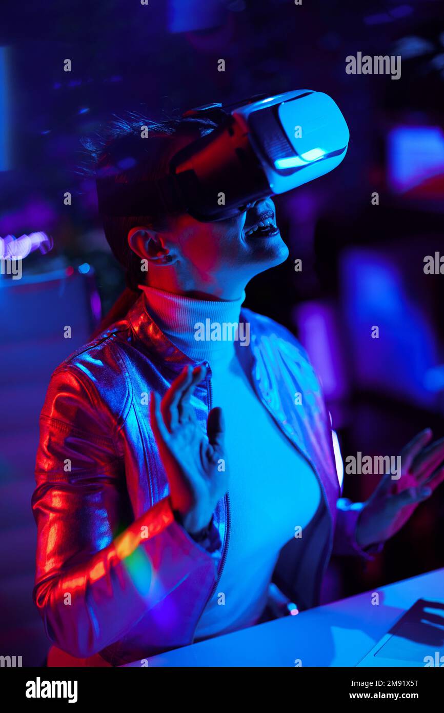 Neon metaverse futuristic concept. smiling stylish woman in vr headset exploring metaverse in ...