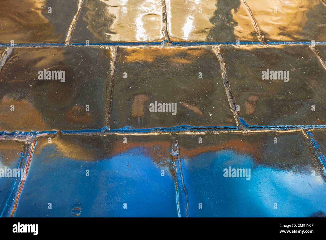 Close-up view of blue gold reflects on glossy floor tiles. Colorful ...