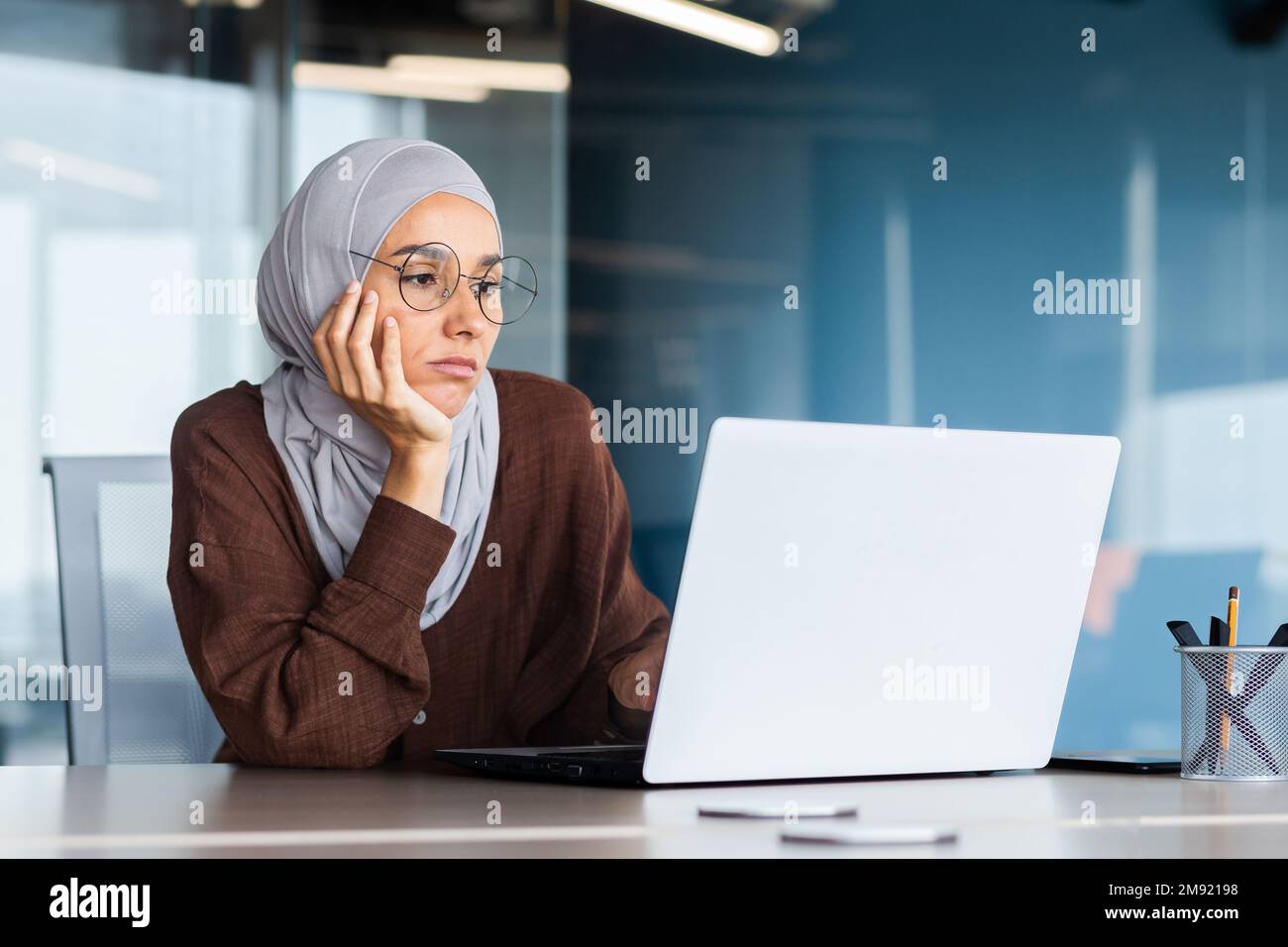 Serious bored businesswoman inside office, muslim woman in hijab ...