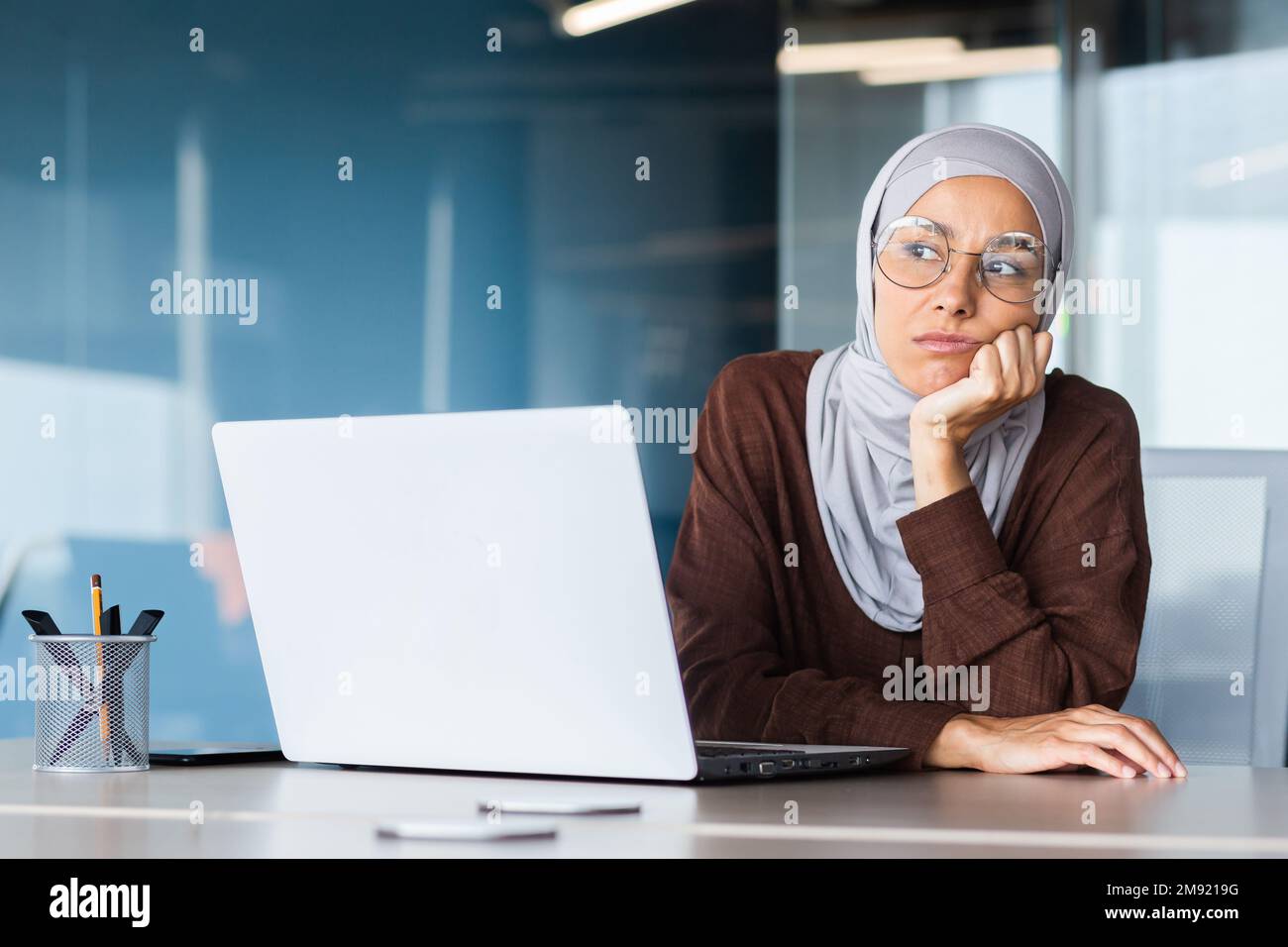 Serious bored businesswoman inside office, muslim woman in hijab ...