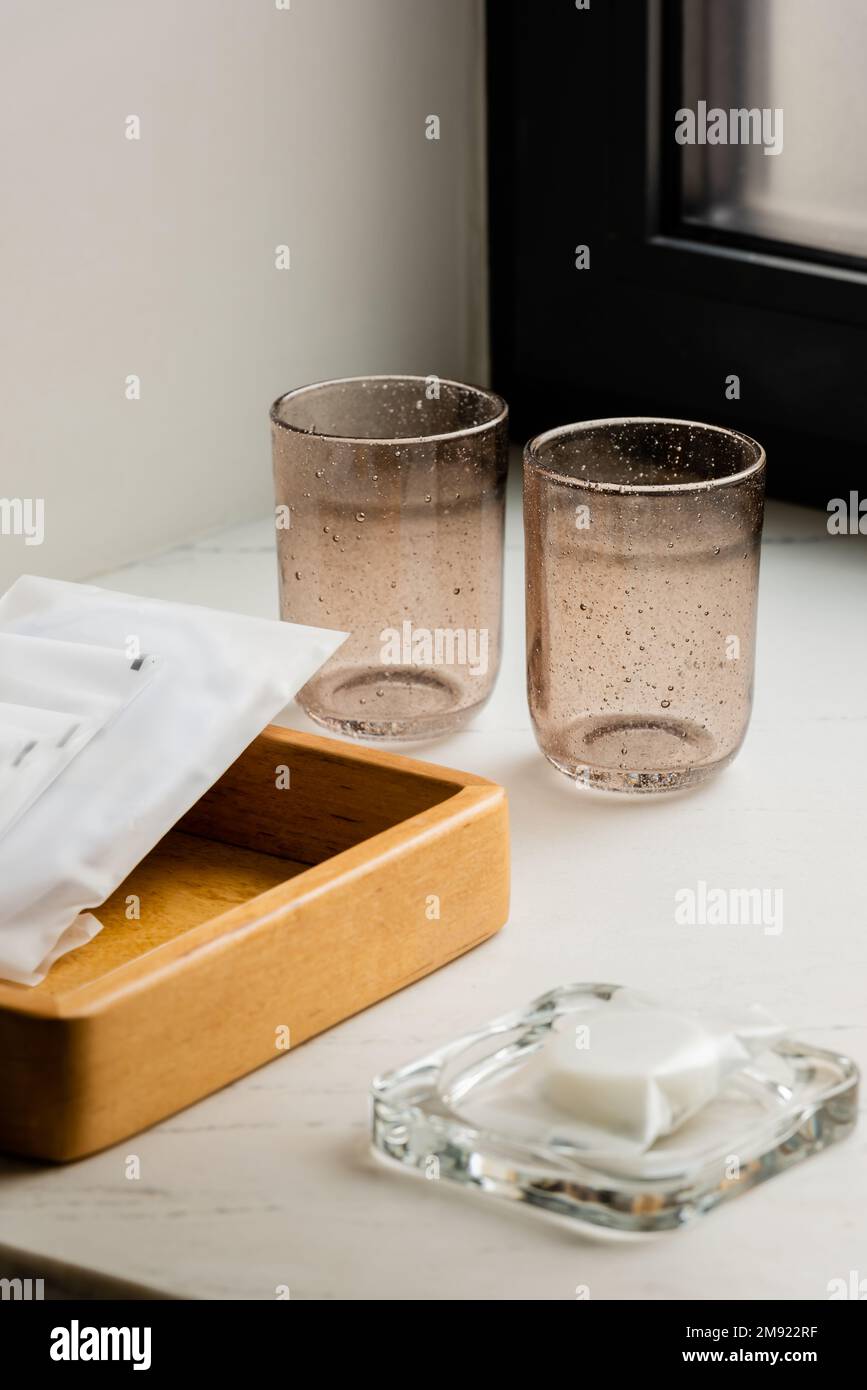 clean glasses near wooden tray with sachets with wet wipes and soap ...