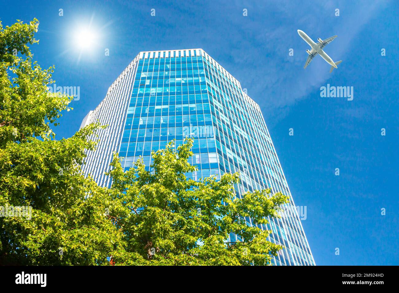 A modern office skyscraper and white passenger aircraft flying over ...