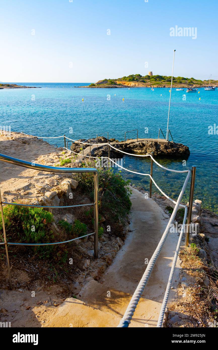 Rock jetty in a rocky corner in the Xinxell cove, with anchored boats ...