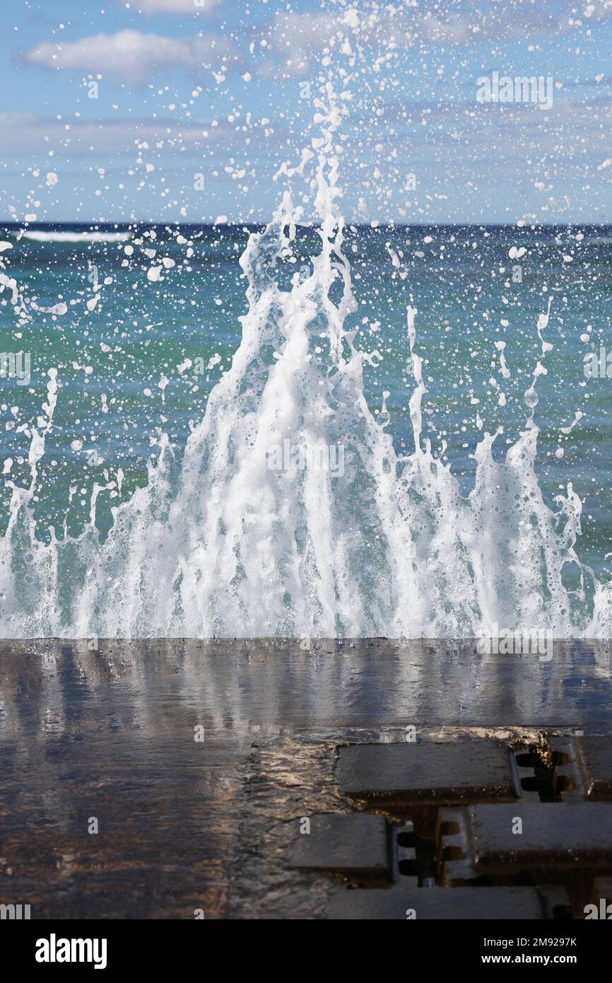 Tropical ocean wave crashing into seawall as coastal sea levels rise in ...