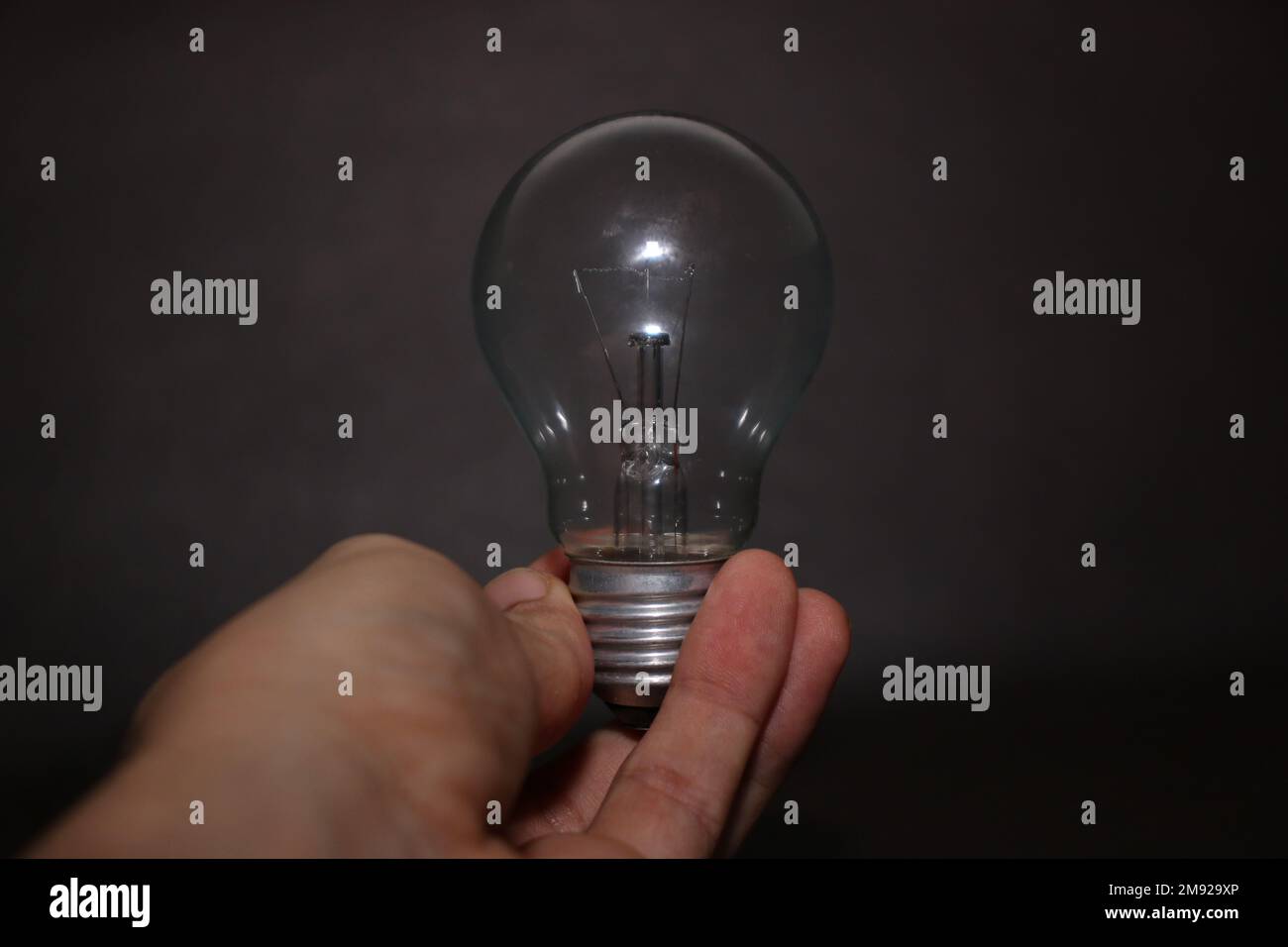 An unlit electric light bulb being held in the hand Stock Photo - Alamy