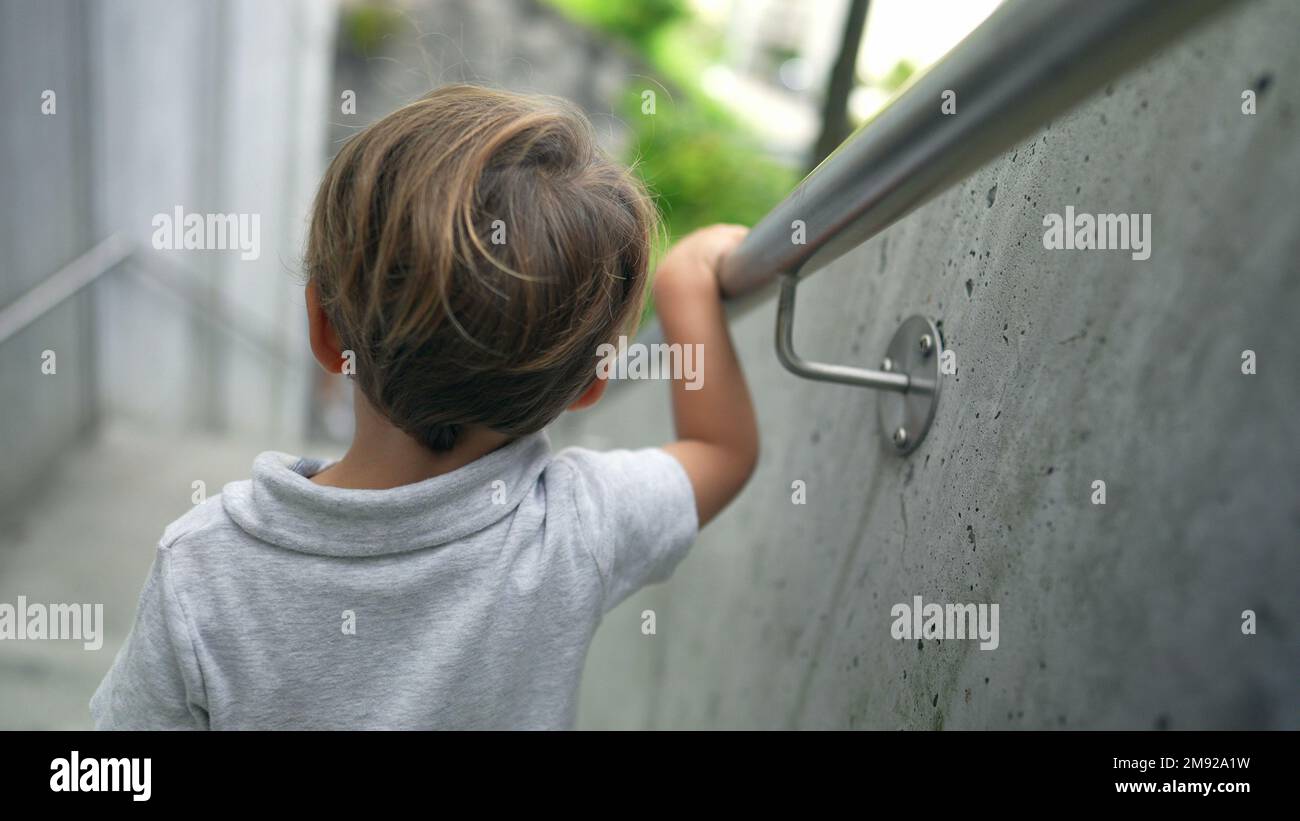 Child walking down stais holding handrail Stock Photo - Alamy