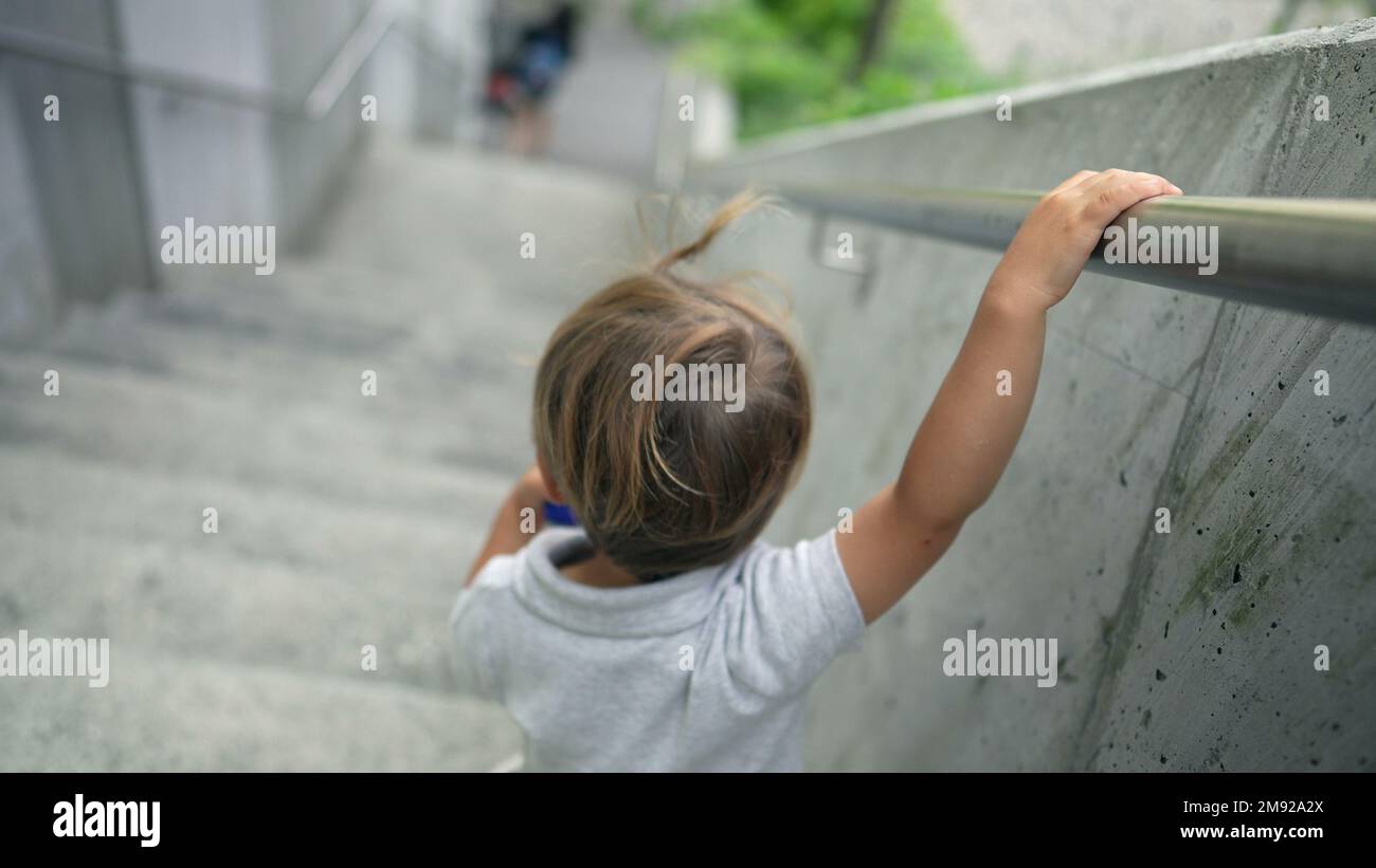Child walking down stais holding handrail Stock Photo - Alamy