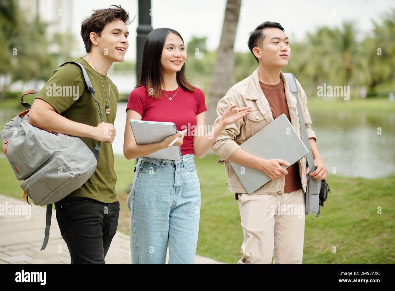 Multi-ethnic group of joyful students walking on campus after classes ...