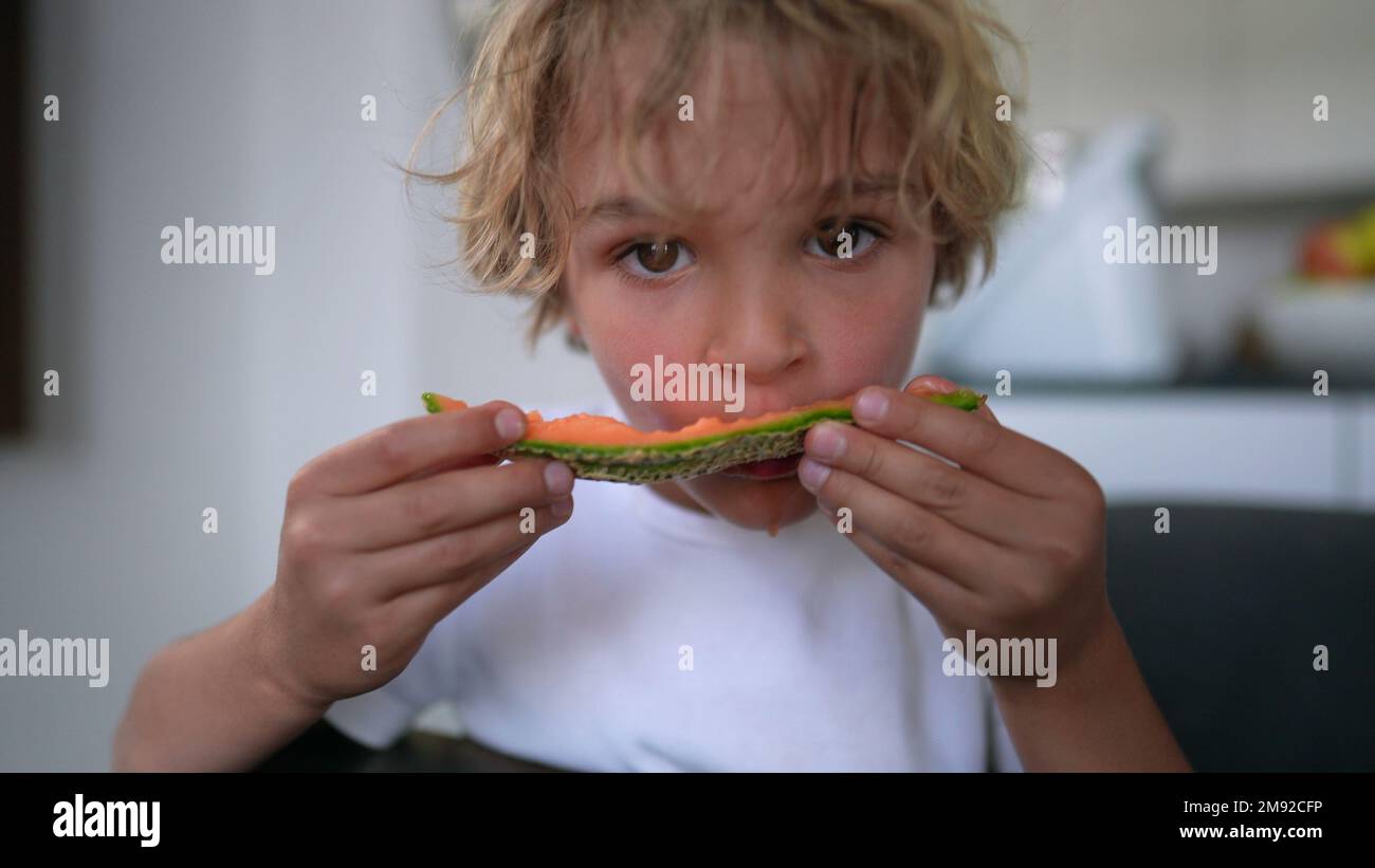 Child eating melon fruit. Portrait kid eating healthy food Stock Photo ...