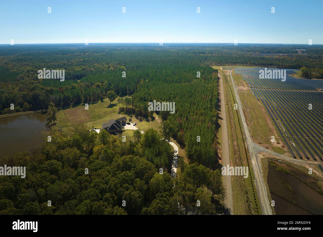 Aerial view of a house near big electric power plant with many rows of ...