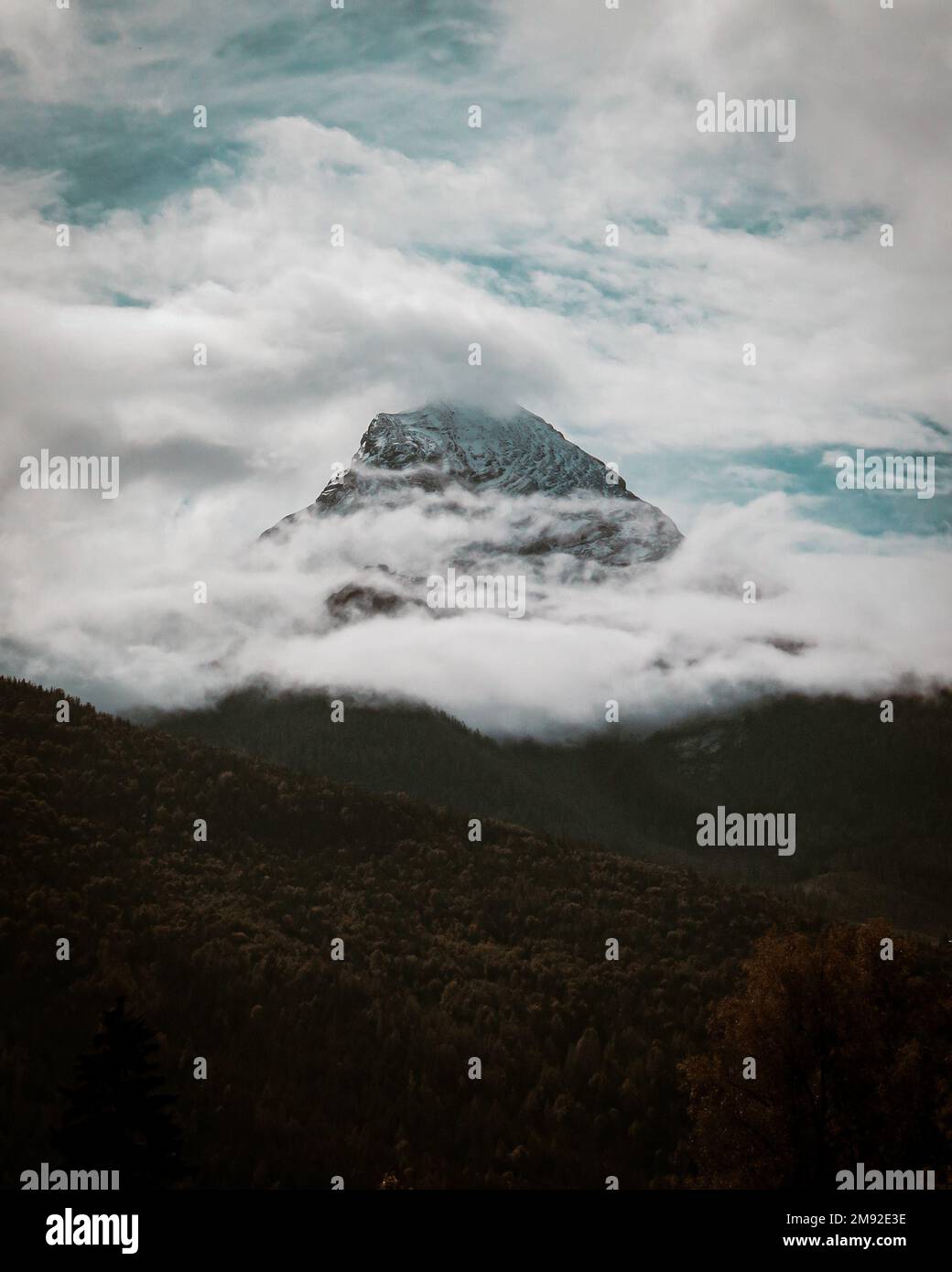 A vertical aerial view of a mountain summit covered with clouds on a ...