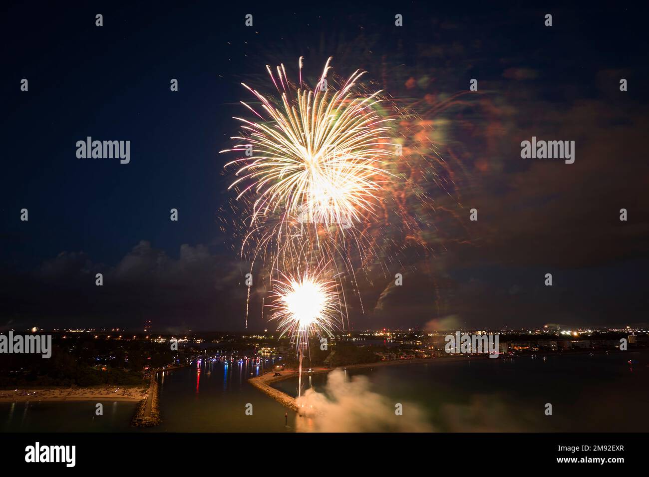 Aerial view of bright fireworks exploding with colorful lights over sea ...