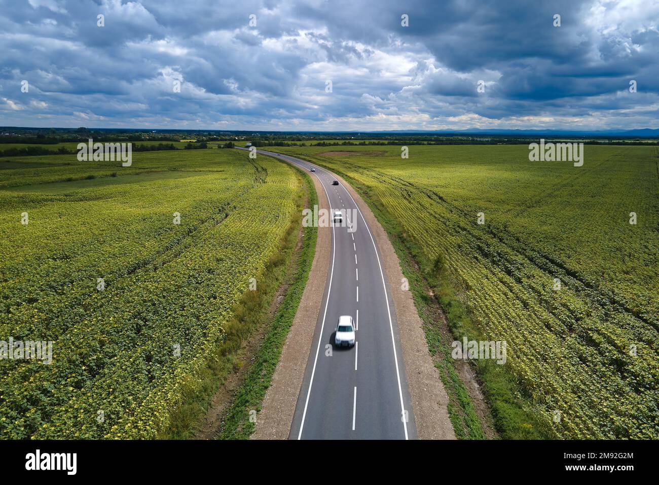 Aerial view of intercity road between green agricultural fields with ...