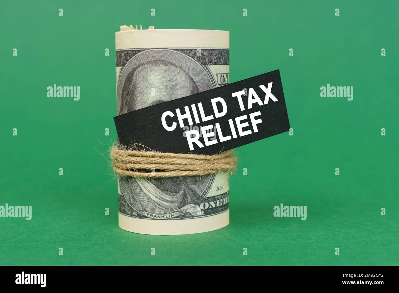 Business concept. On a green surface, rolled dollars with a black sign ...