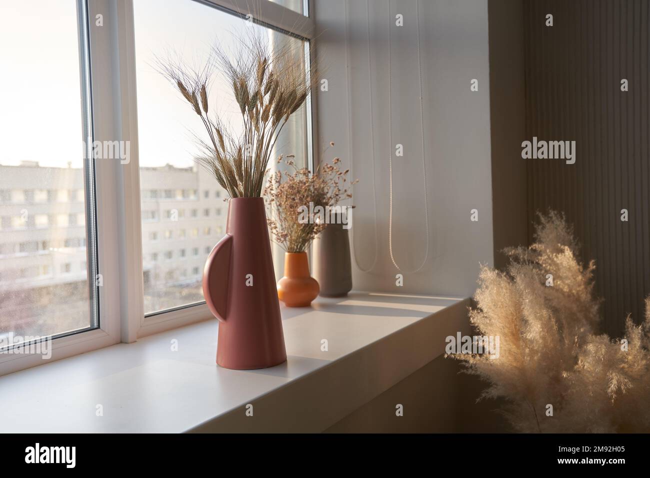 Dried flowers in an old ceramic vase on the window. Sunlight and sun ...