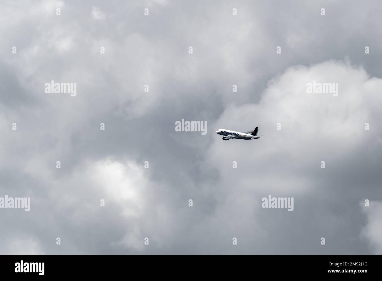 An aerial shot of the white airplane flying through the gray clouds in ...