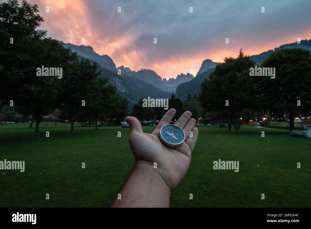 Compass held with one hand on a background mountain landscape in ...