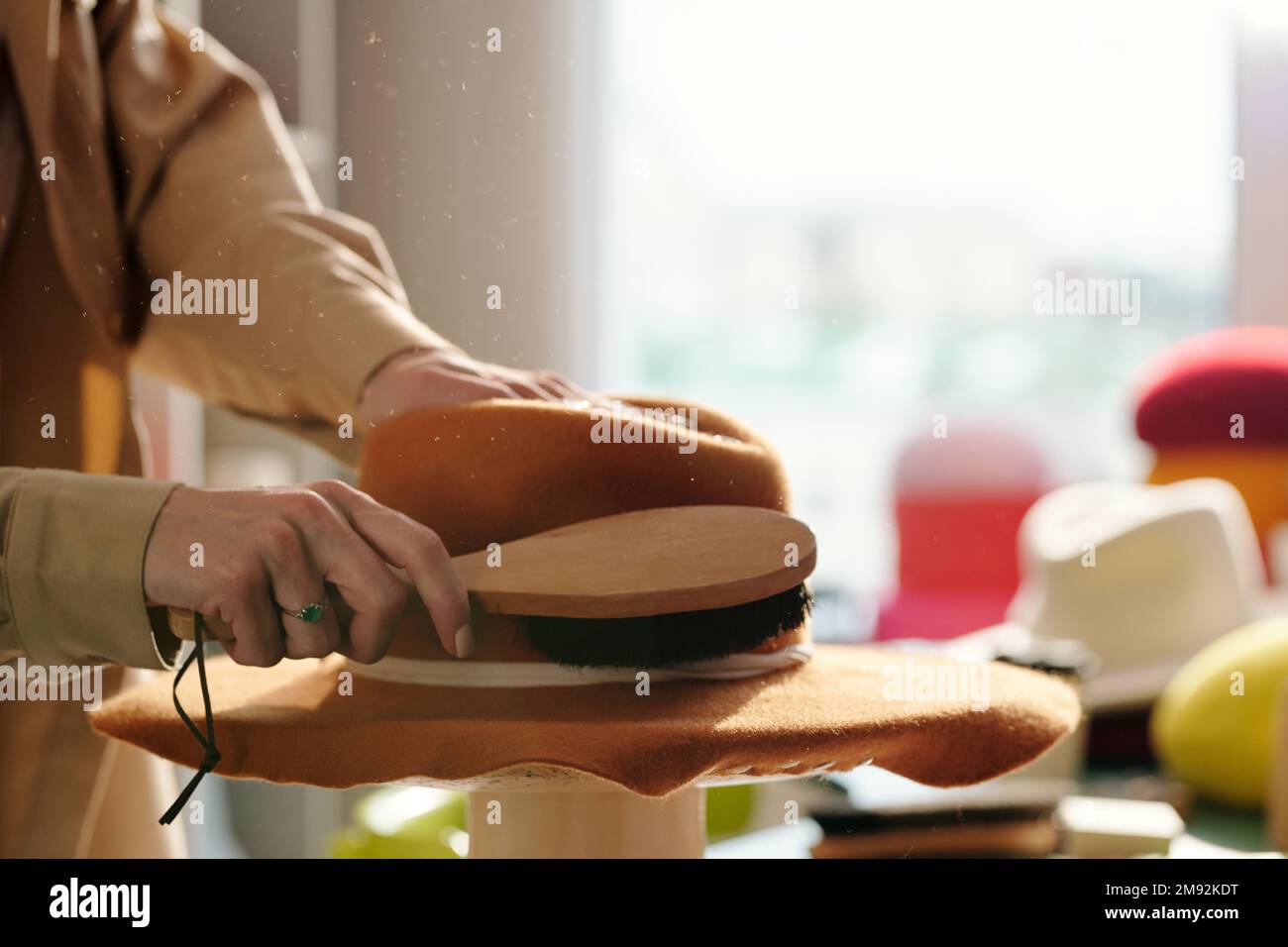 Close-up of young creative female artisan brushing off flecks of dust ...