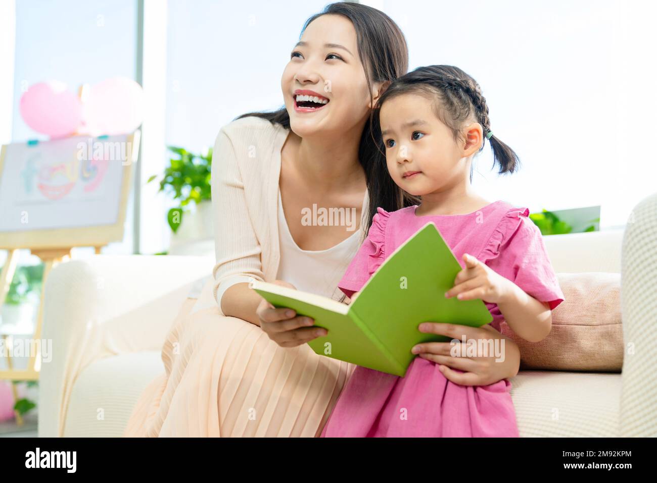 The little girl and her mother read a book together Stock Photo - Alamy