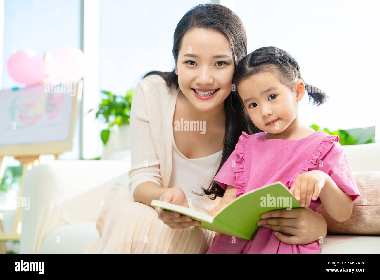 The little girl and her mother read a book together Stock Photo - Alamy