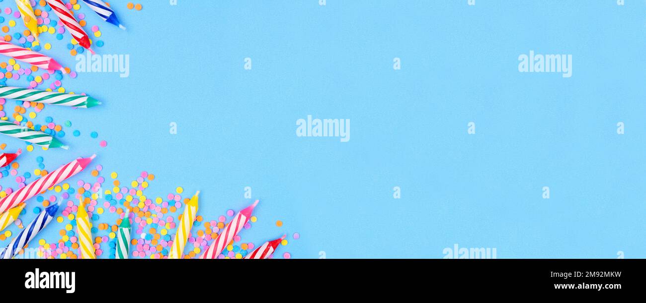 Birthday cake candles with candy sprinkles. Top view banner with corner border on a blue ...