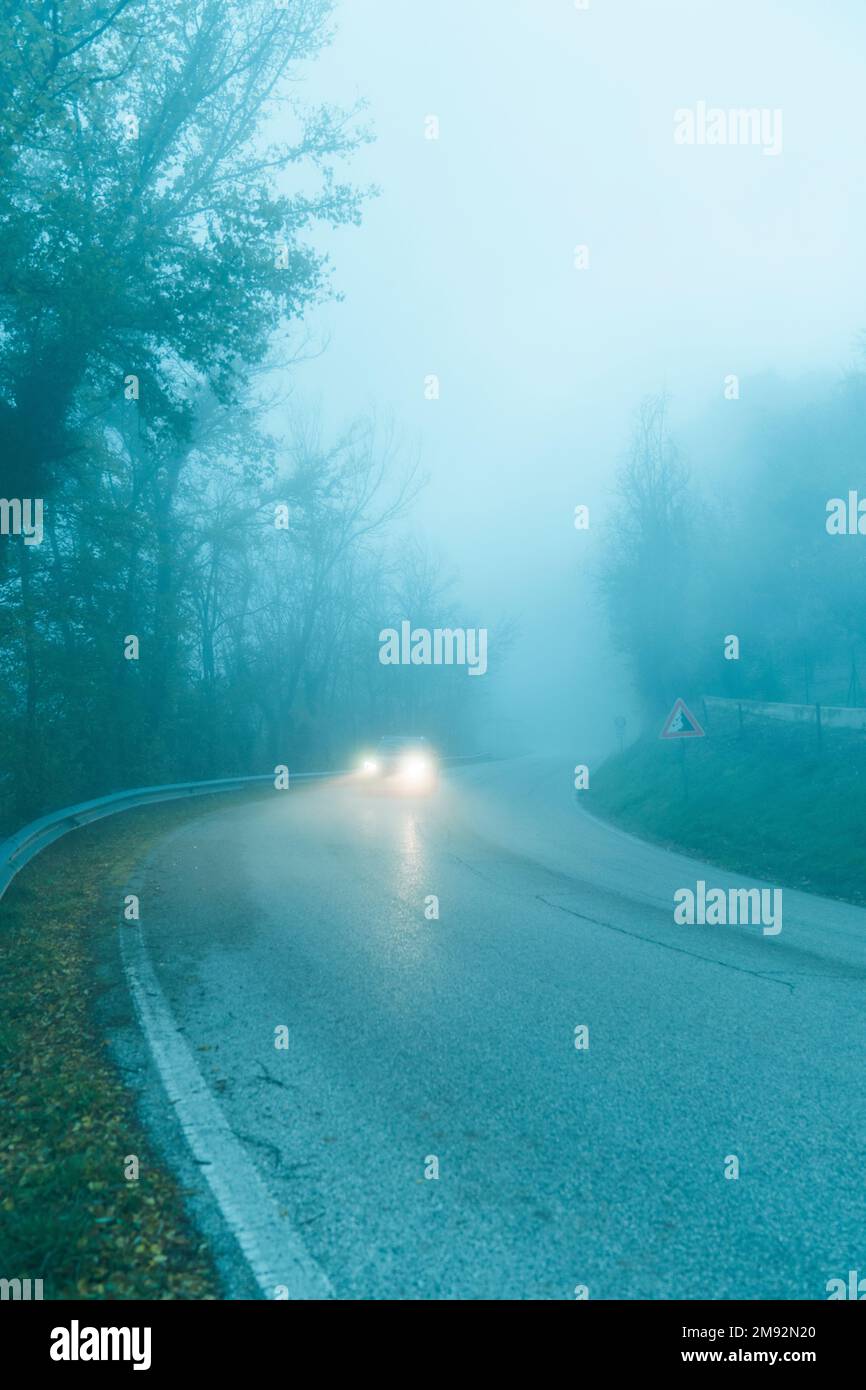 Scenic view of lonely car with glowing headlights on asphalt road in ...