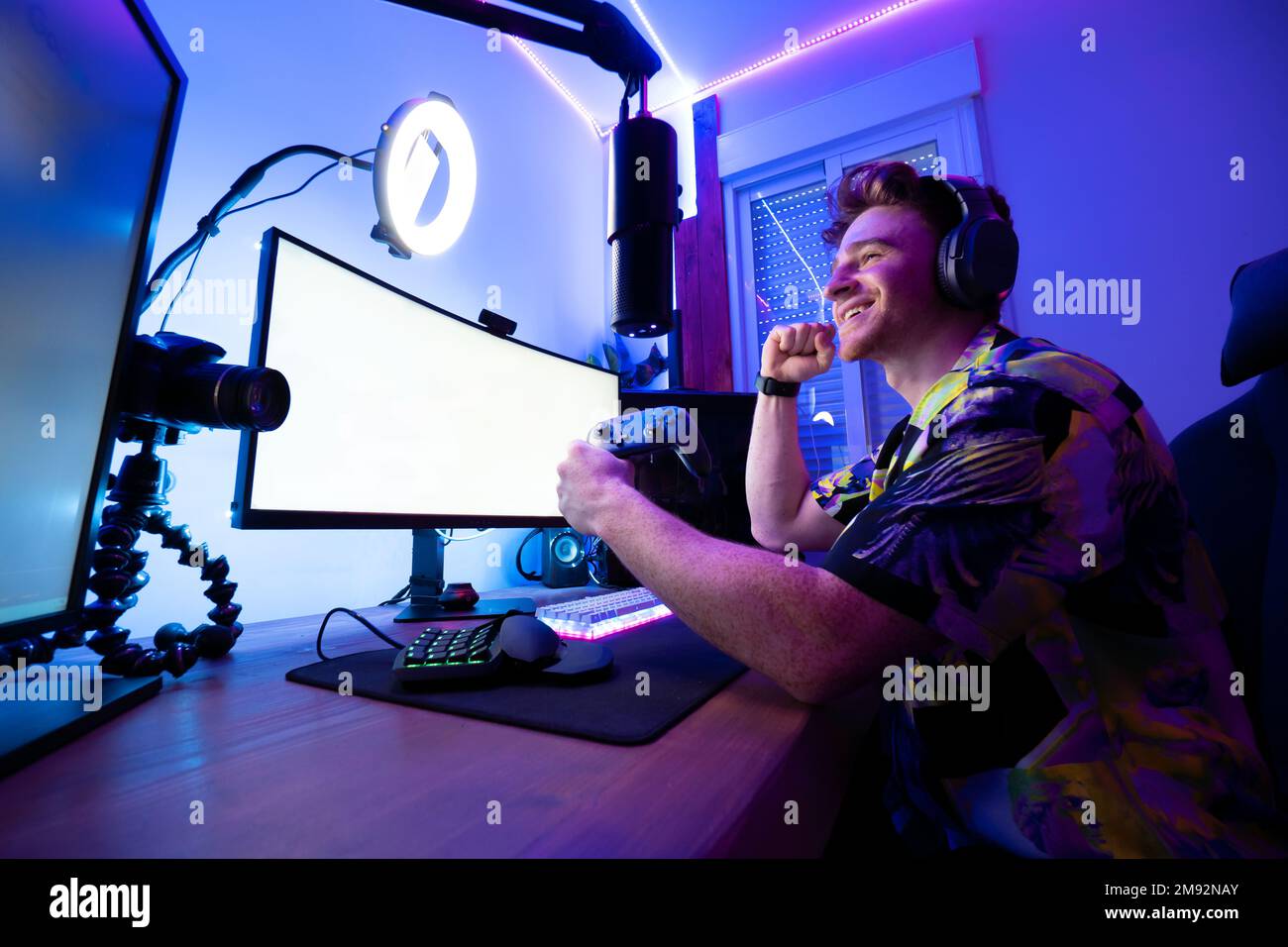 Low angle side view of positive young male gamer in colorful shirt and ...