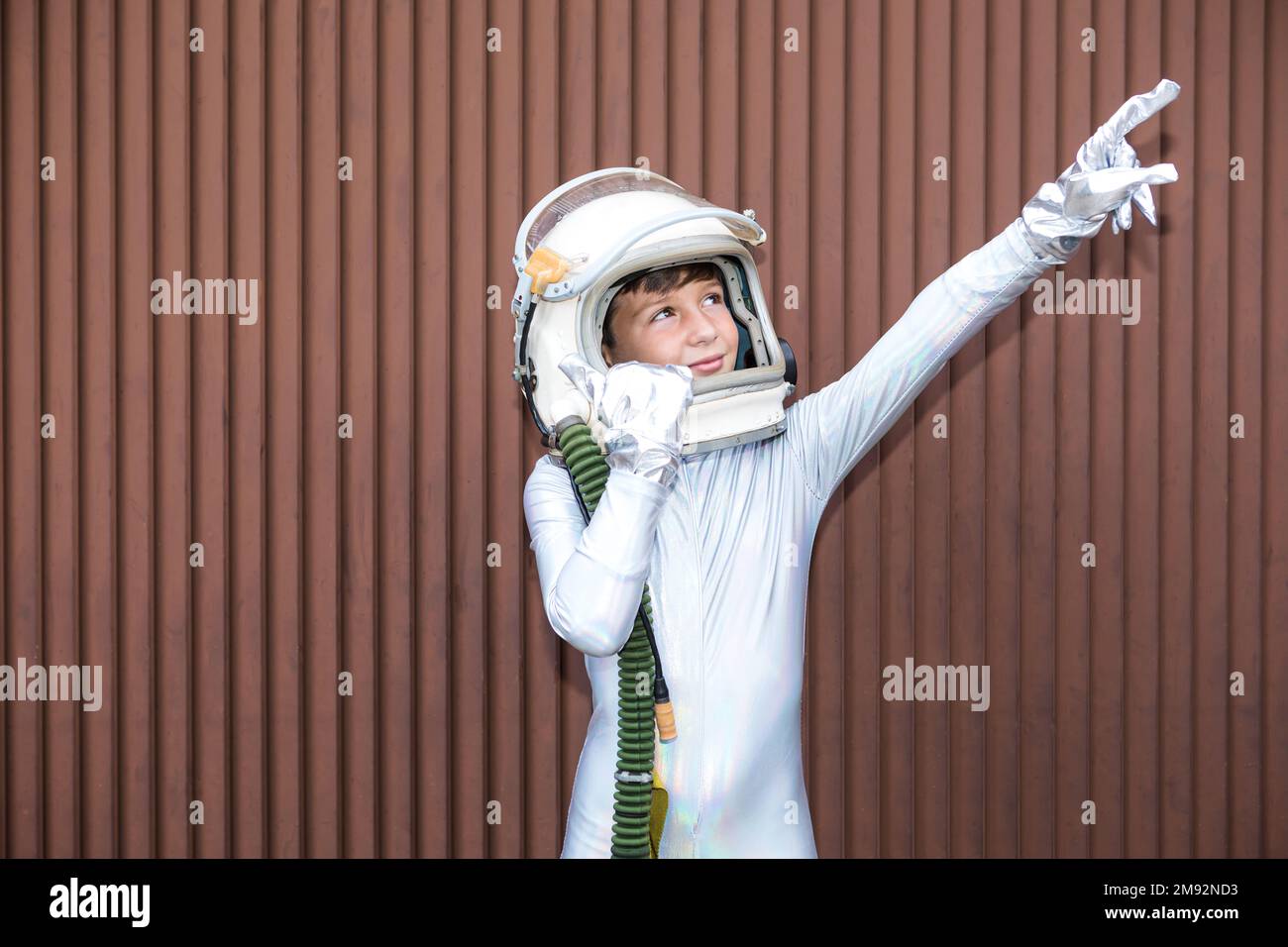 Curious preteen child in space suit standing in front of brown ribbed ...