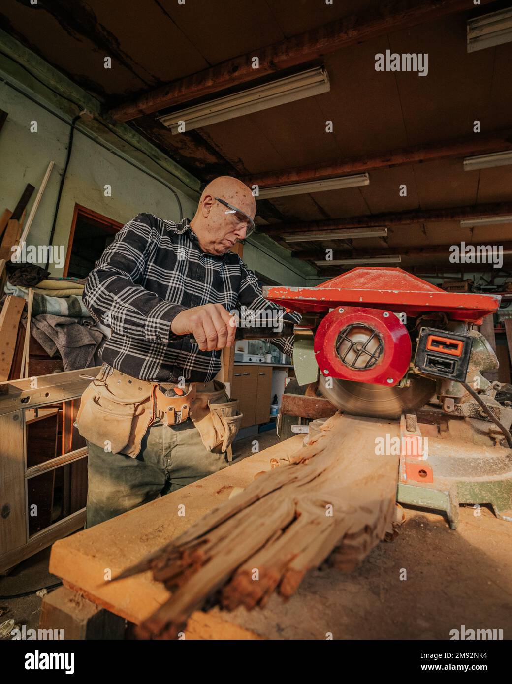 Concentrated mature male woodworker in protective goggles and ...