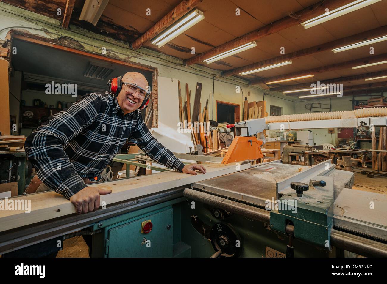 Concentrated mature male woodworker in protective goggles and ...