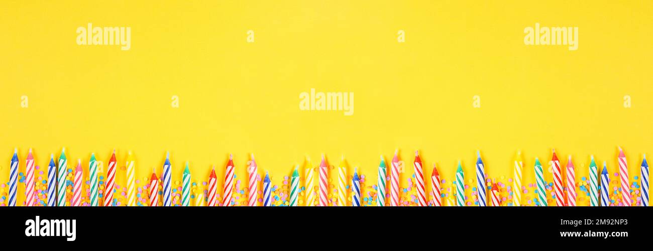 Birthday cake candles with candy sprinkles. Top down view banner with bottom border on a yellow ...