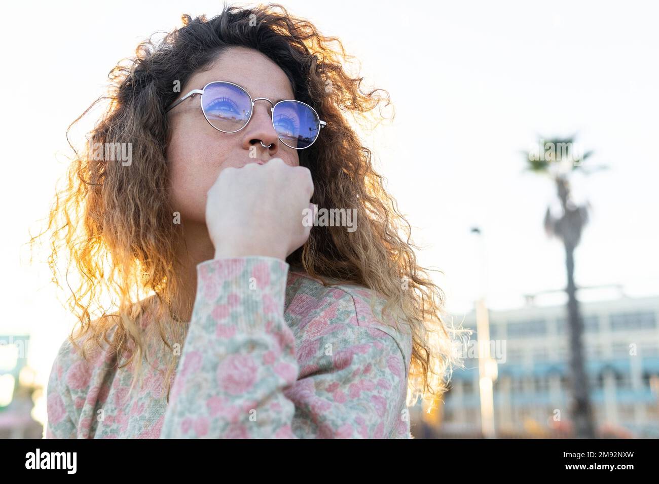 From below young dreamy female with curly hair in glasses and casual ...