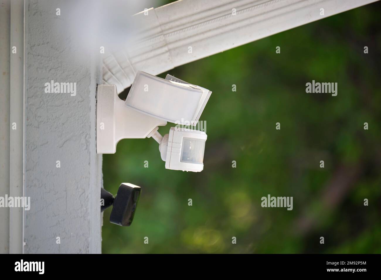 Motion sensor with light detector mounted on exterior wall of private ...