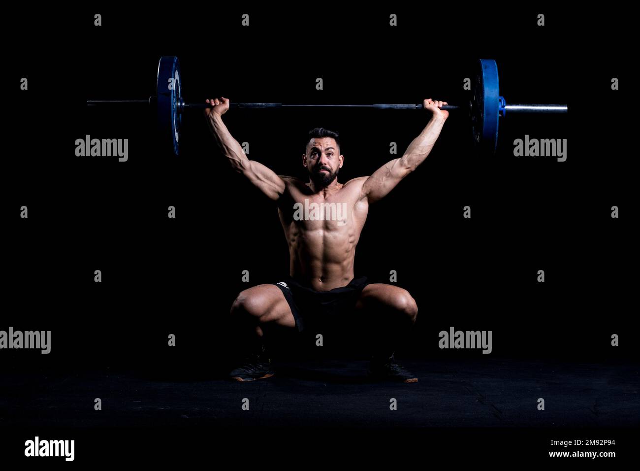 Full body of powerful male athlete lifting heavy barbell with weights ...
