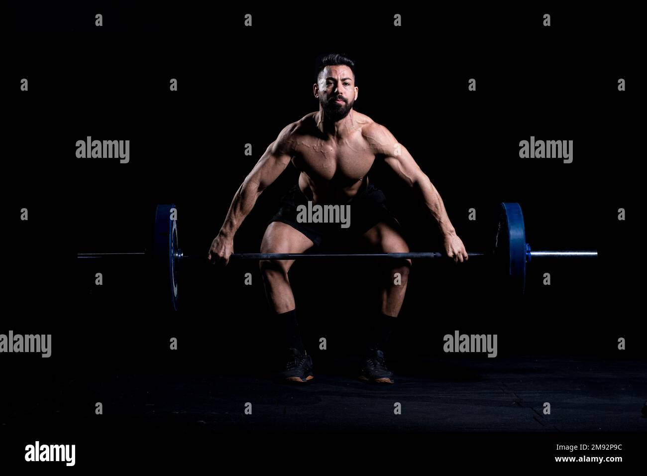 Full body of powerful male athlete lifting heavy barbell with weights ...