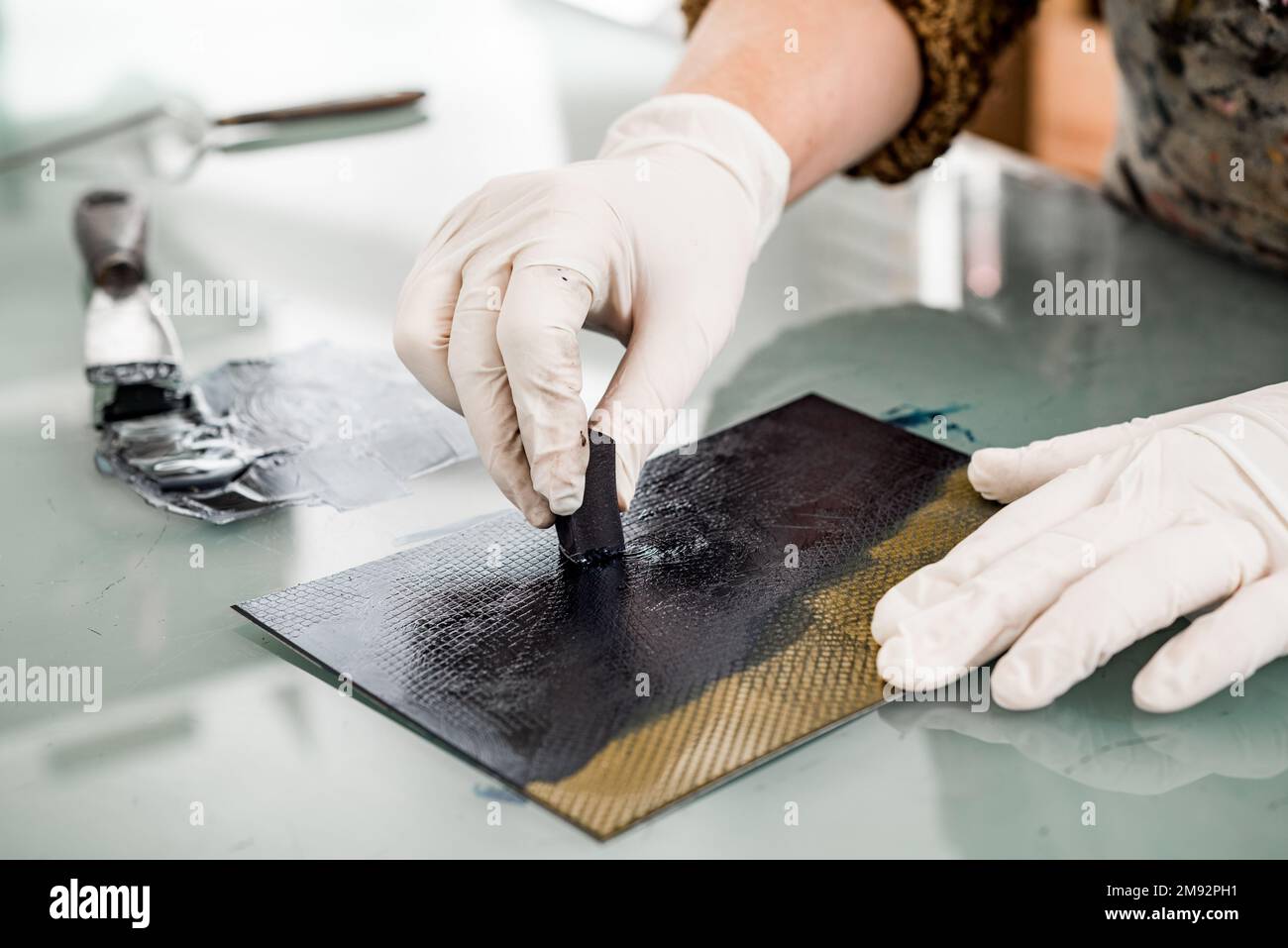From above anonymous female artisan in latex gloves using small sponge ...