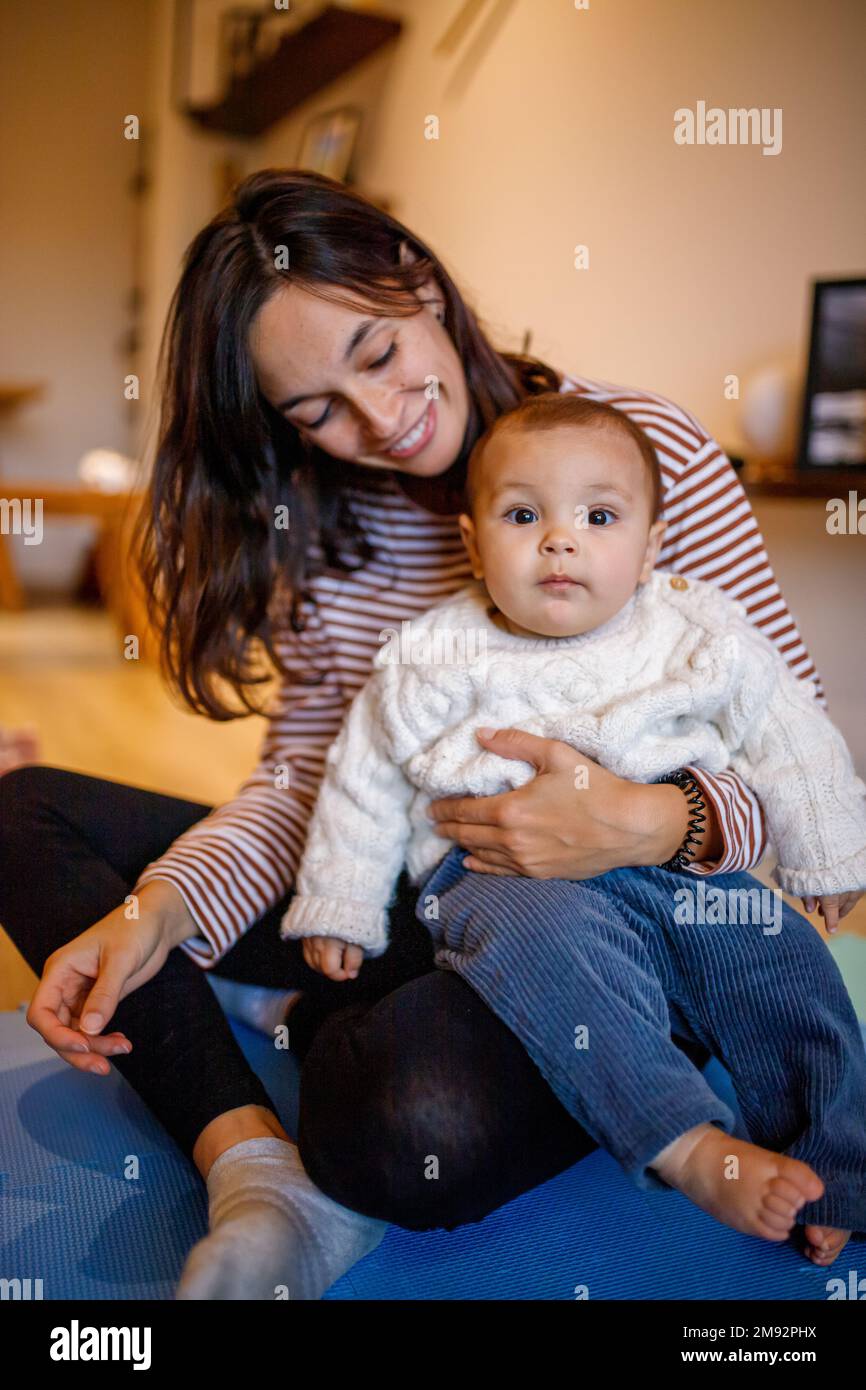 Positive mother in casual clothes smiling and hugging adorable son ...