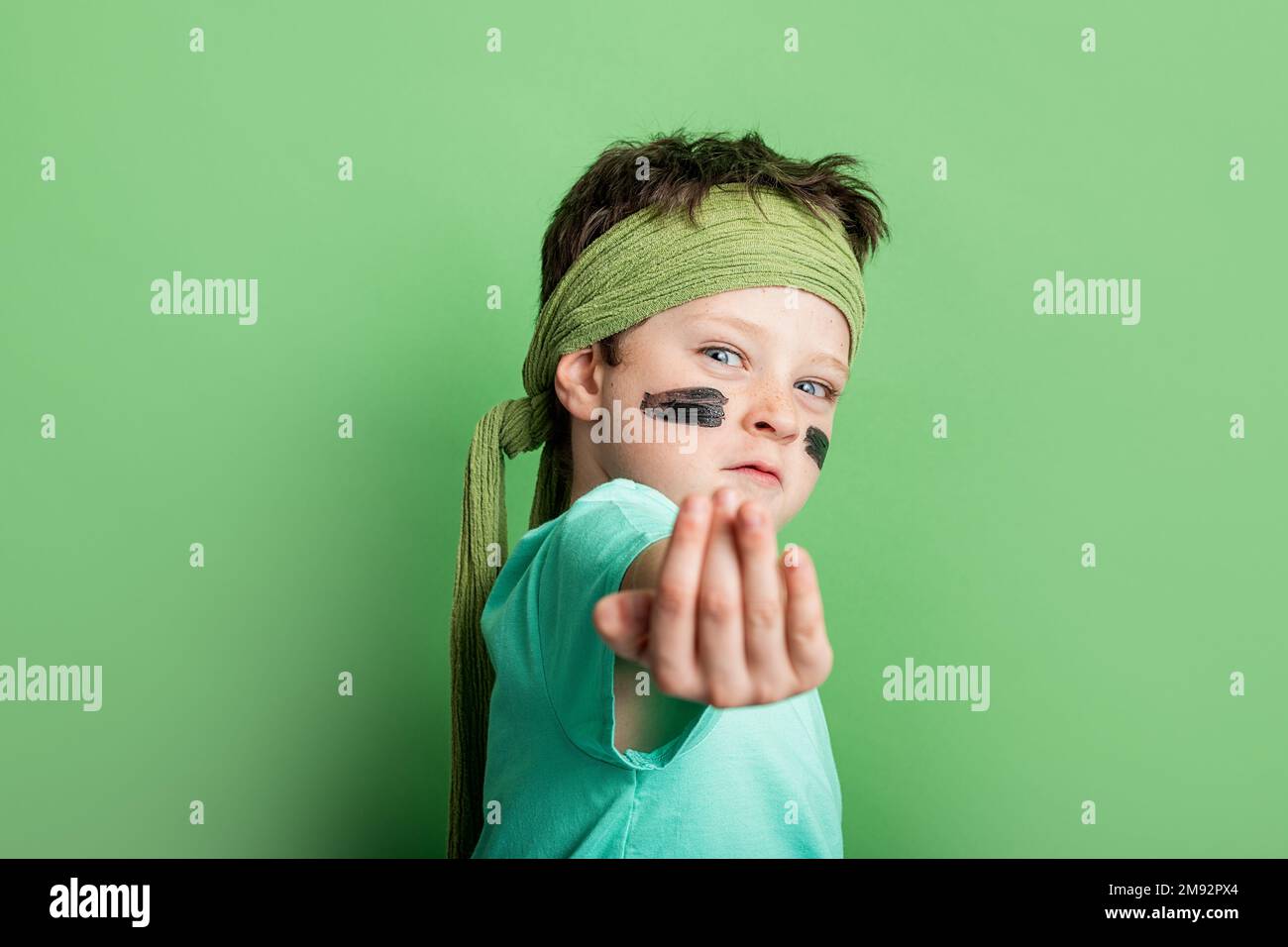 Furious kid with headband and black strips on cheeks calling opponent ...